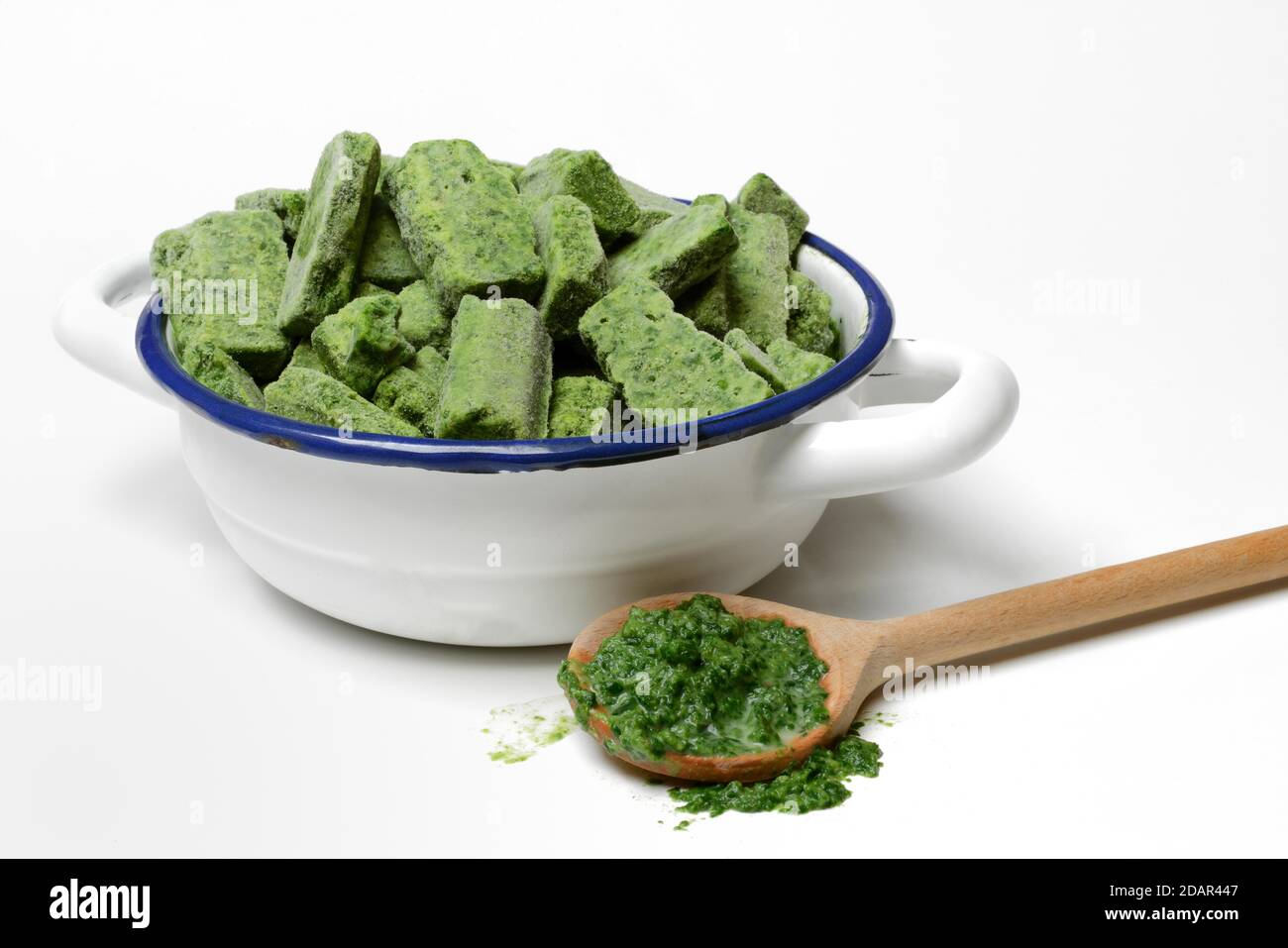 Portioned, frozen creamed spinach in bowl and defrosted spinach in ...