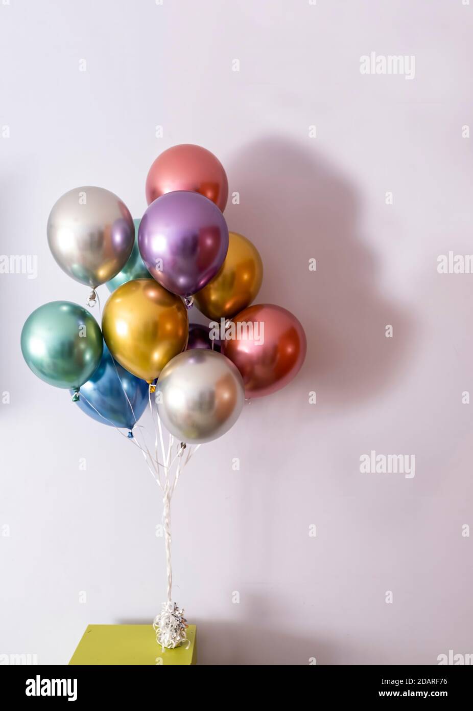 metallic coloured helium balloons tied with a bow and held by a weight ...