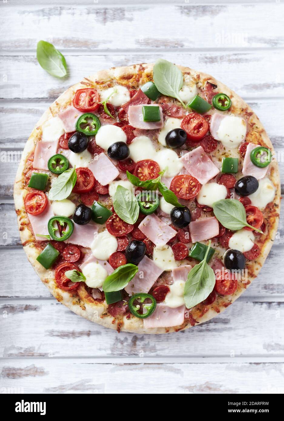 Pizza with ham, mozzarella cheese, cherry tomatoes, green and jalapeno pepper, black olives and ...