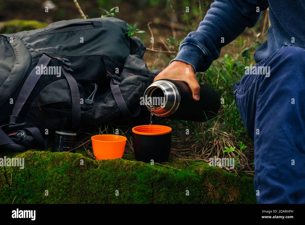 Drinking tea during hike. Man hand pouring hot tea from black thermos ...