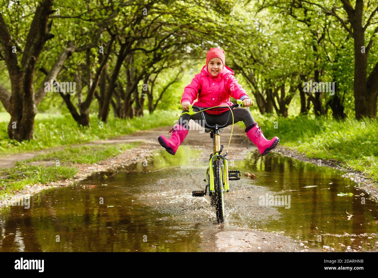 little girl riding bike in water puddle Stock Photo - Alamy
