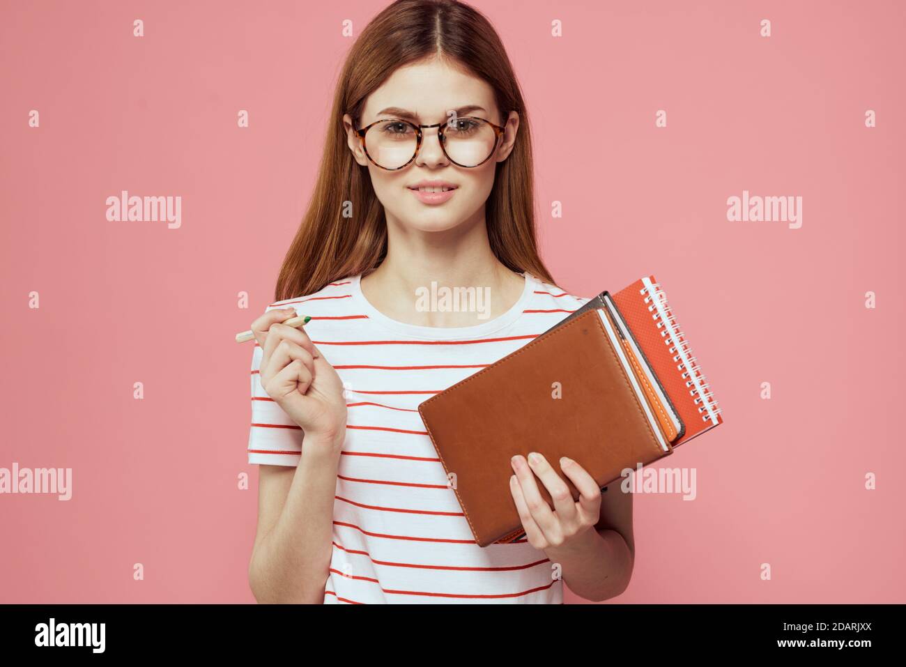 female student with notepads on pink background gesturing with her ...
