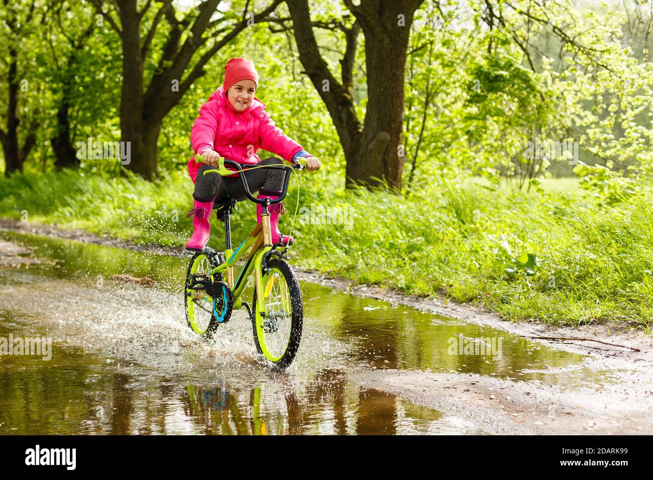 little girl riding bike in water puddle Stock Photo - Alamy