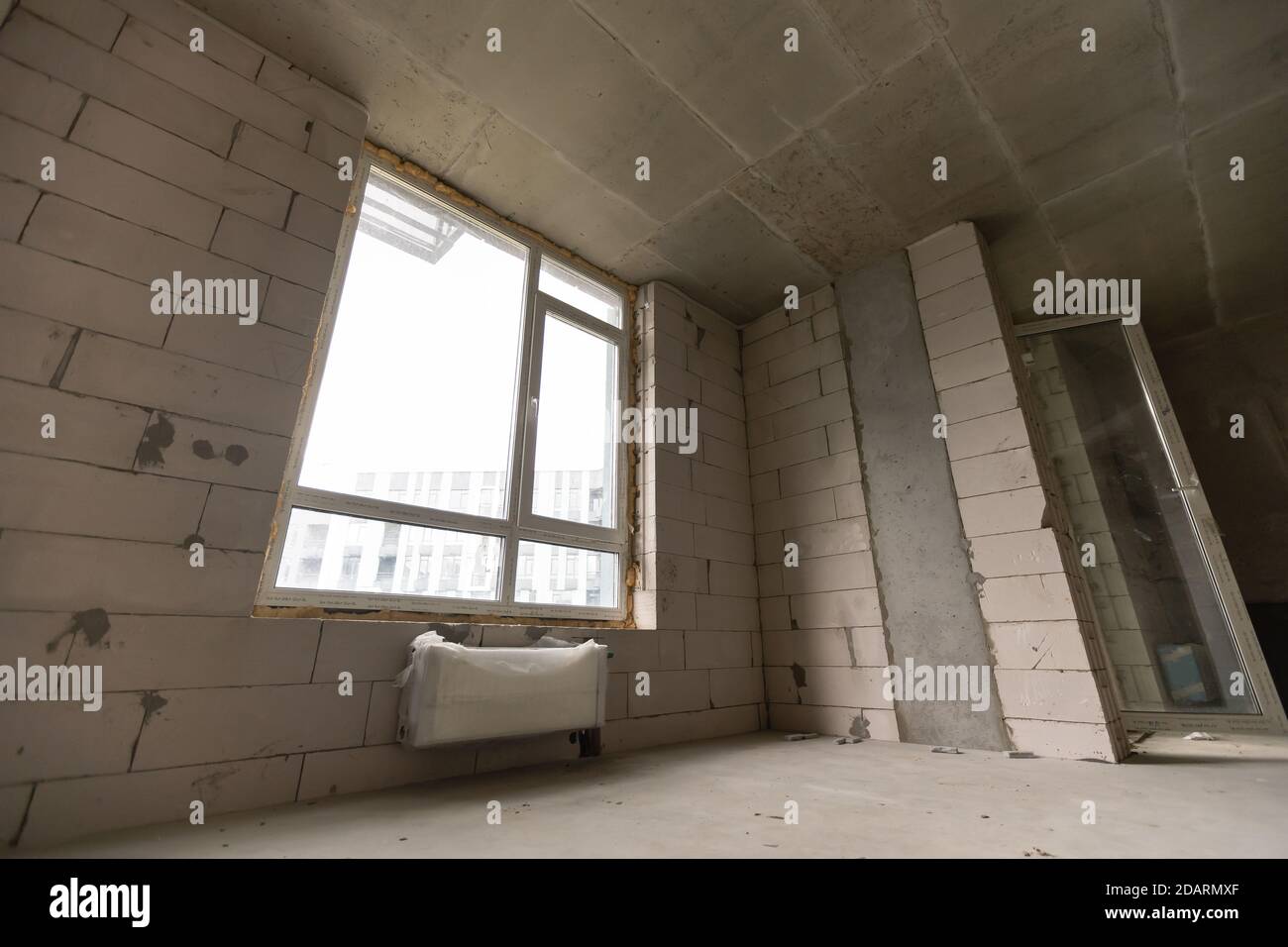 A new unfinished apartment room with the bare brick walls without ...