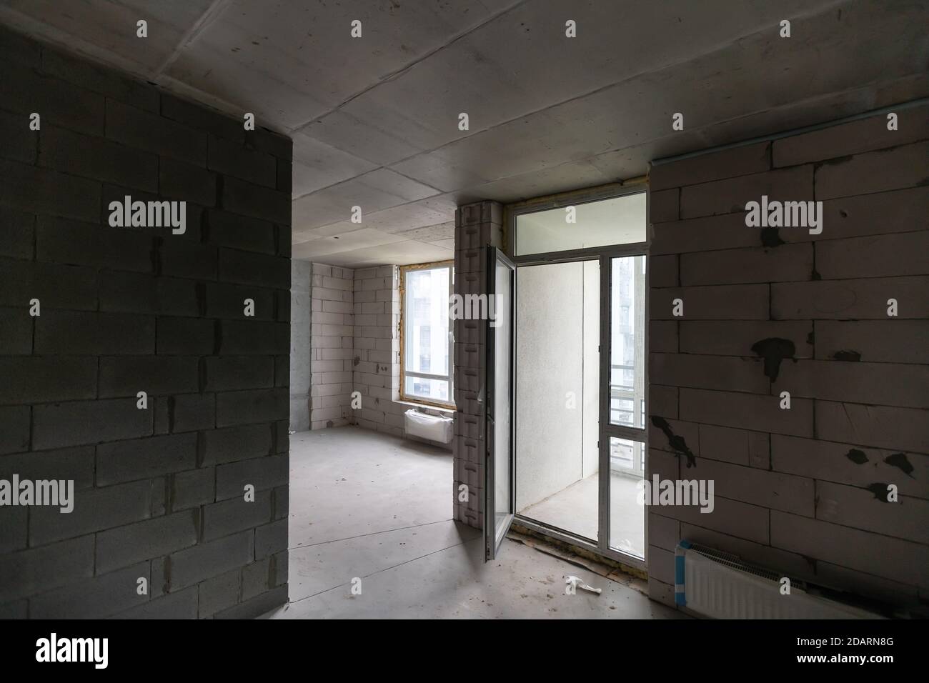 A new unfinished apartment room with the bare brick walls without ...