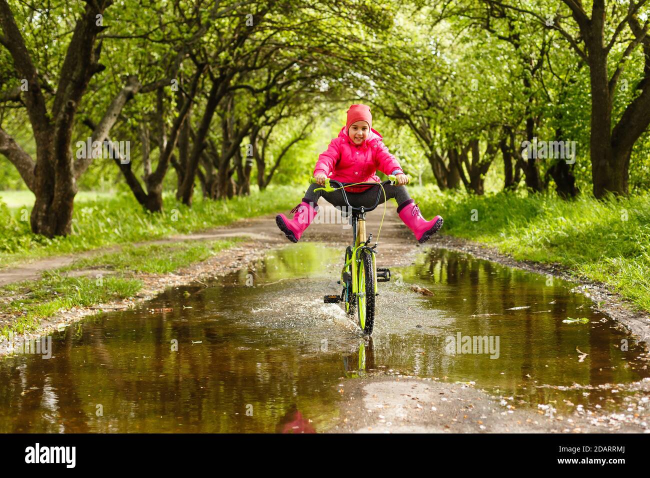 little girl riding bike in water puddle Stock Photo - Alamy