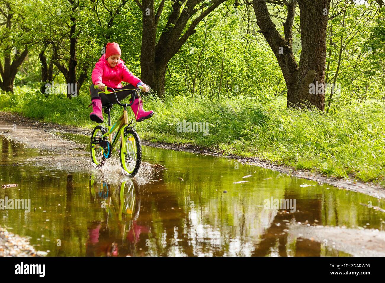 little girl riding bike in water puddle Stock Photo - Alamy