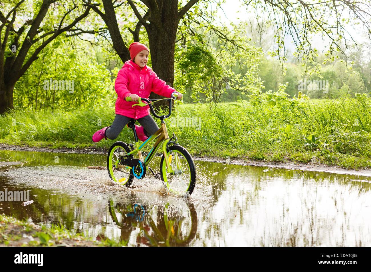 little girl riding bike in water puddle Stock Photo - Alamy