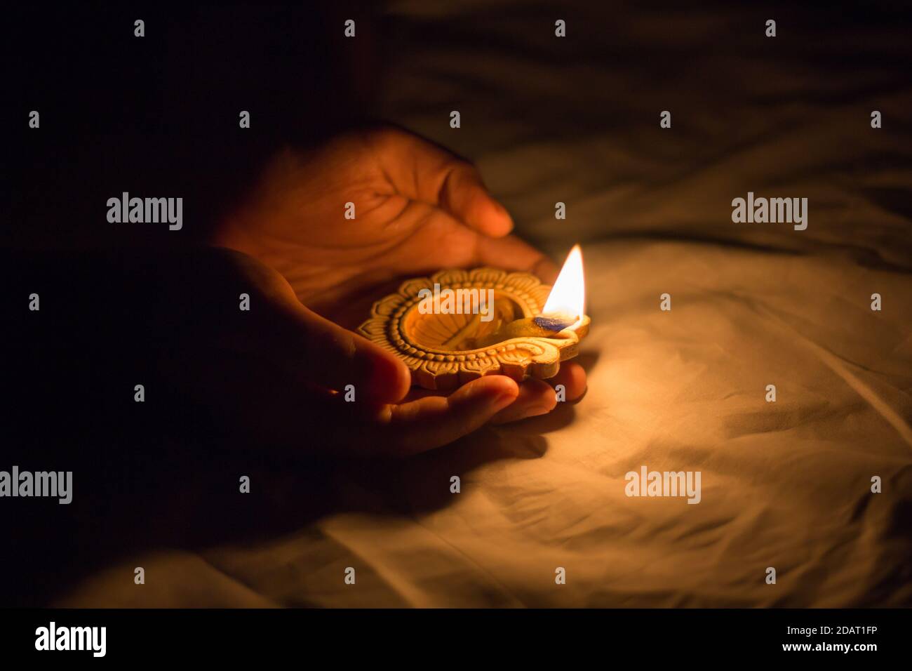 hands holding diwali diya or indian traditional oil lamp made of clay ...