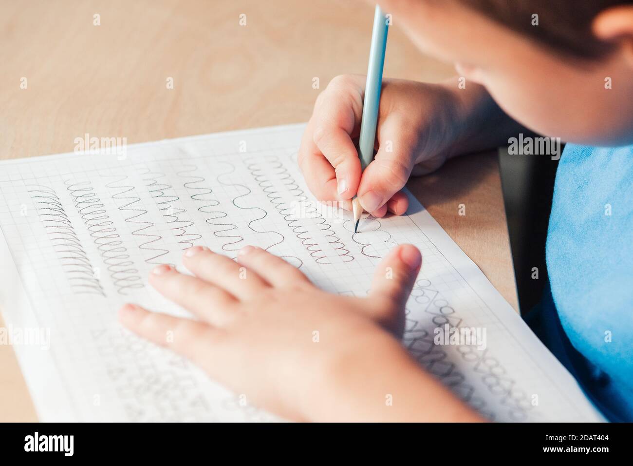 Close up of schoolboy doing writing task. Prewriting practice to ...