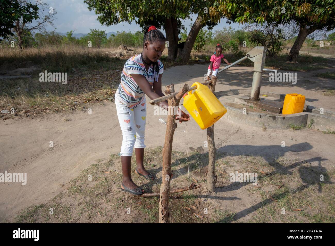 Young girl washing hands on gallon of water recycled and adapted on ...