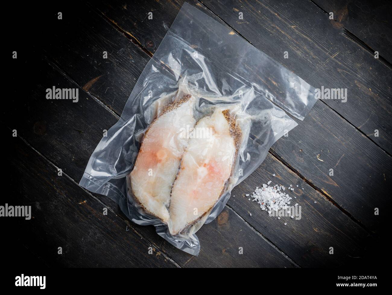 Frozen Greenland halibut steaks vacuum-packed on the wood cutting board ...