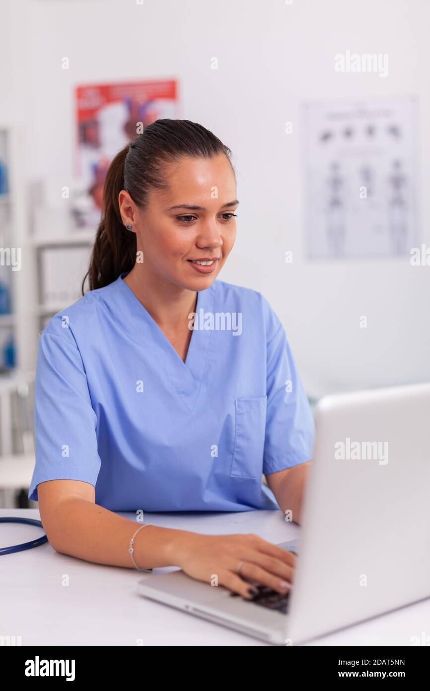 Medical nurse typing on laptop test results of patient in hospital ...
