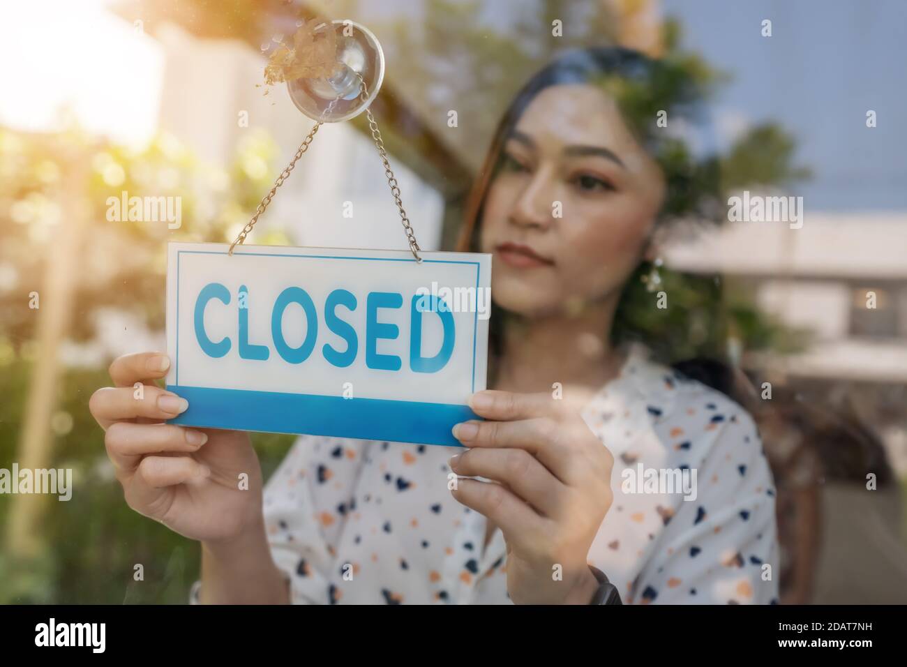 young woman owner turning closed sign in door of store Stock Photo - Alamy