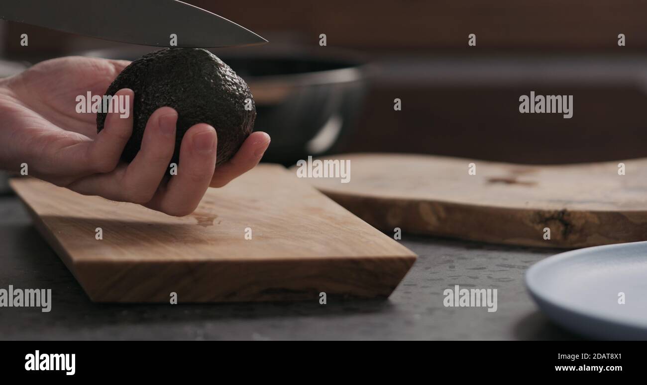 Slow motion man cuts ripe avocado to open on kitchen, wide photo Stock ...