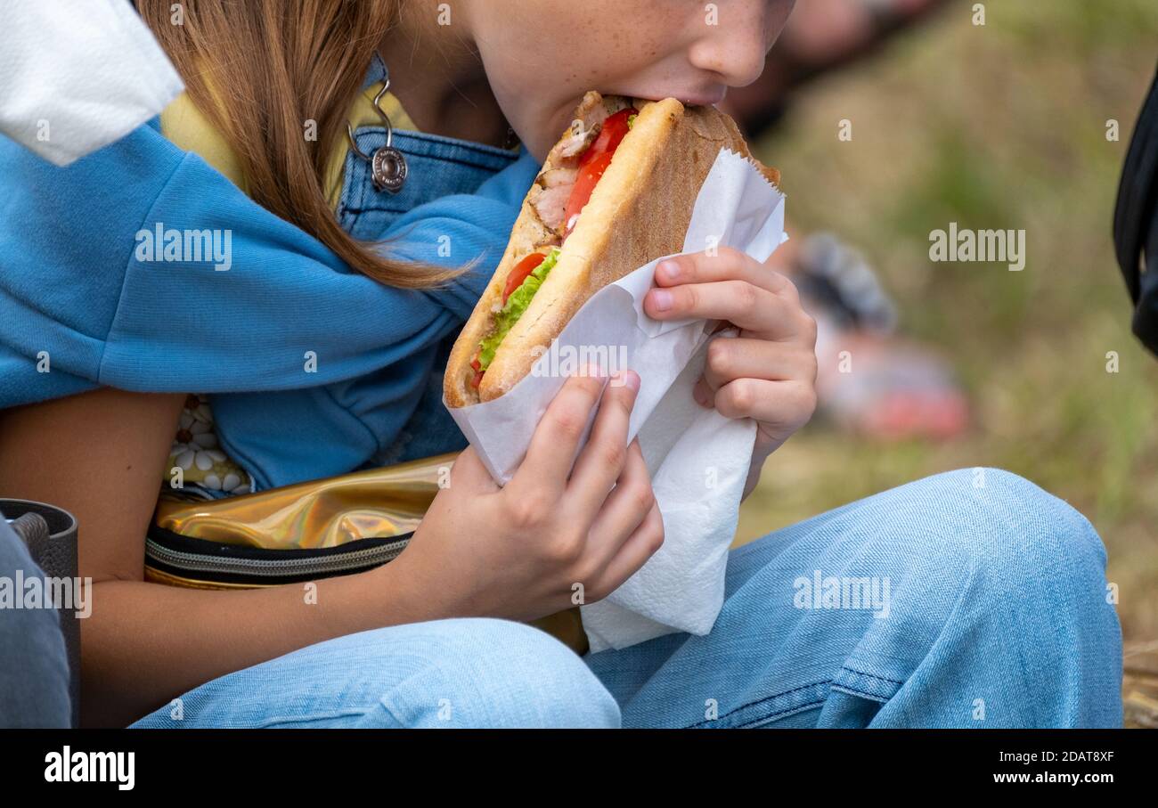 Crop girl eating sandwich in park Stock Photo - Alamy