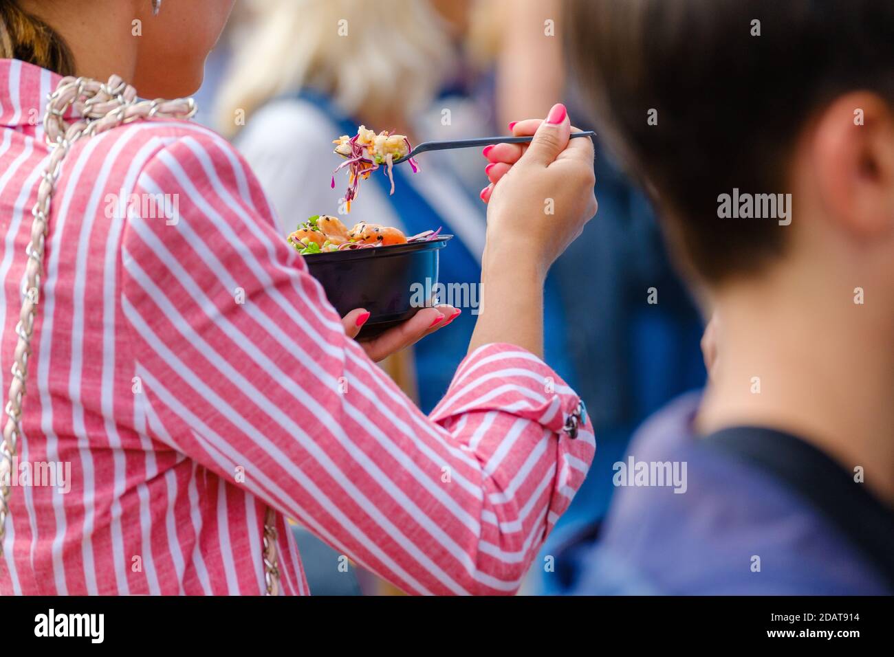 Crop woman eating salad in crowd Stock Photo - Alamy
