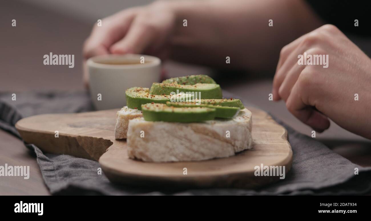 Slow motion man eating breakfast with caibatta with avocado and cream ...