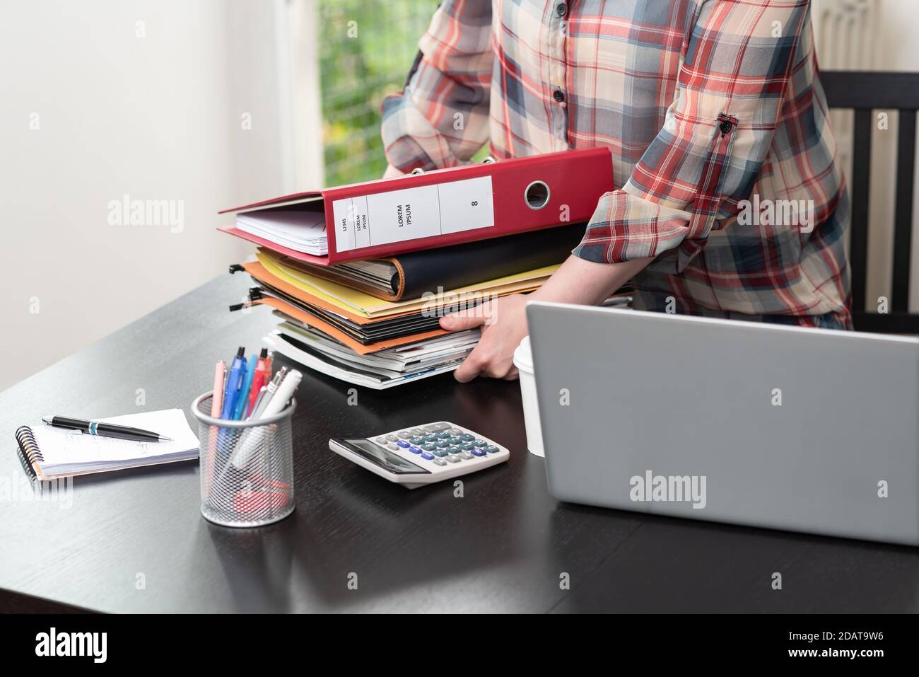 Businesswoman putting a stack of binders and folders on her desk Stock ...