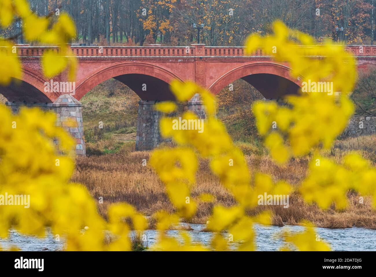 an old brick bridge in the fall and a river flowing under the bridge to ...