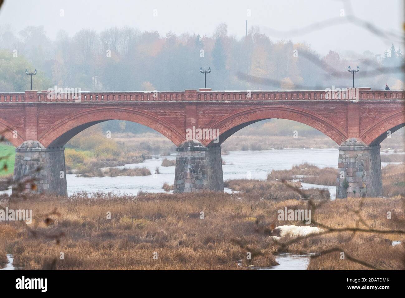 an old brick bridge in the fall and a river flowing under the bridge to ...