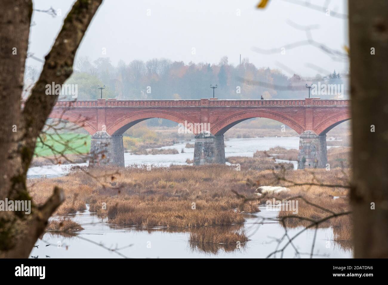 an old brick bridge in the fall and a river flowing under the bridge to ...