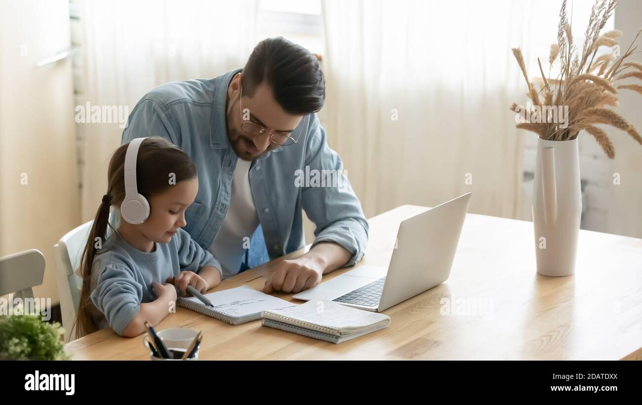 Caring father helping little daughter with school homework at home ... Caring father helping little daughter with school homework at home ...