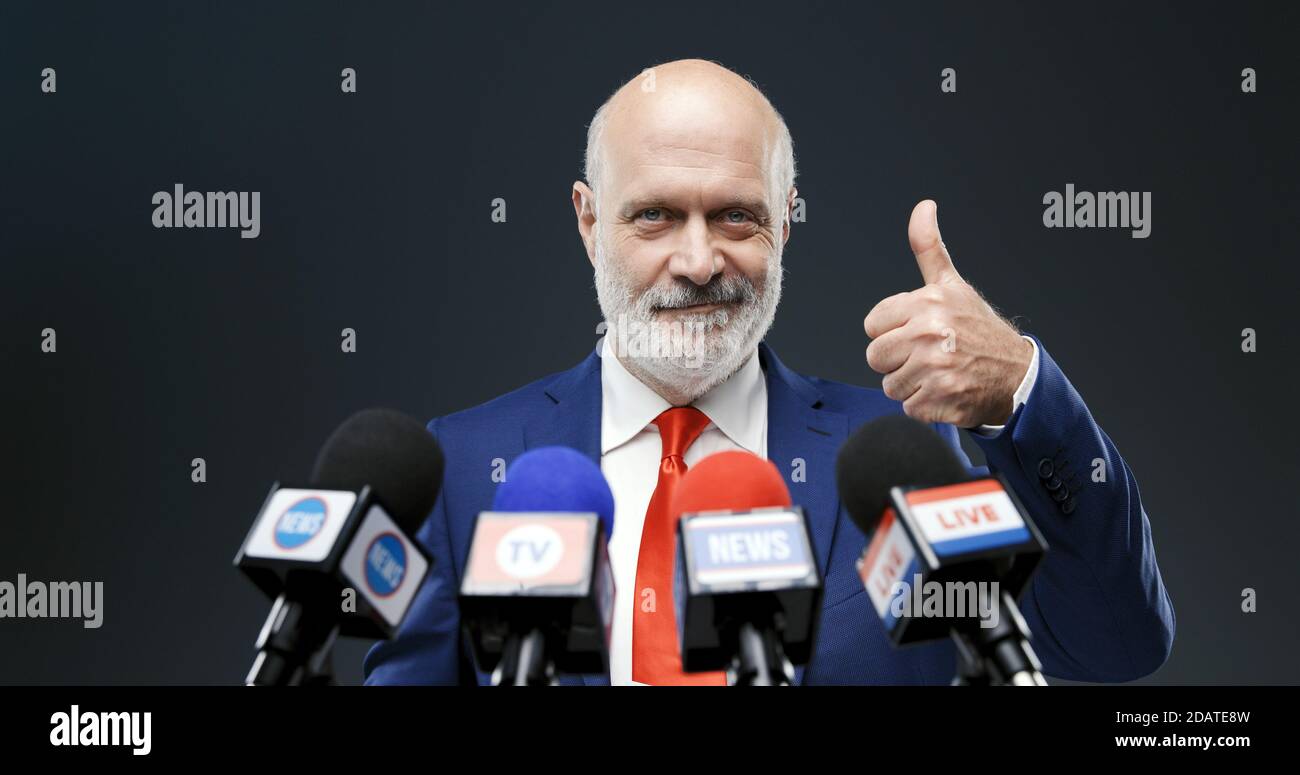 Politician giving a thumbs up during a press conference and smiling ...