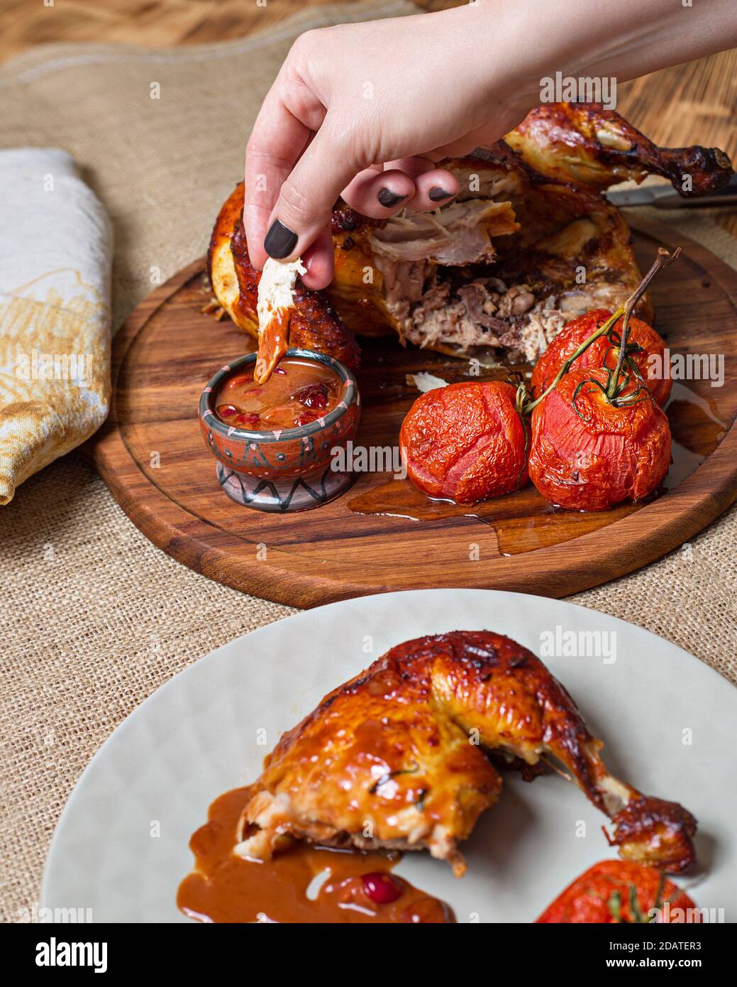 Chicken baked in the oven with tomatoes and sauce. With a woman's hand ...
