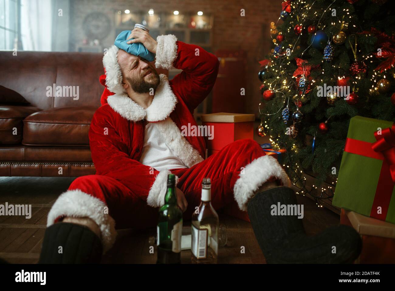 Santa with hangover sitting under christmas tree Stock Photo - Alamy