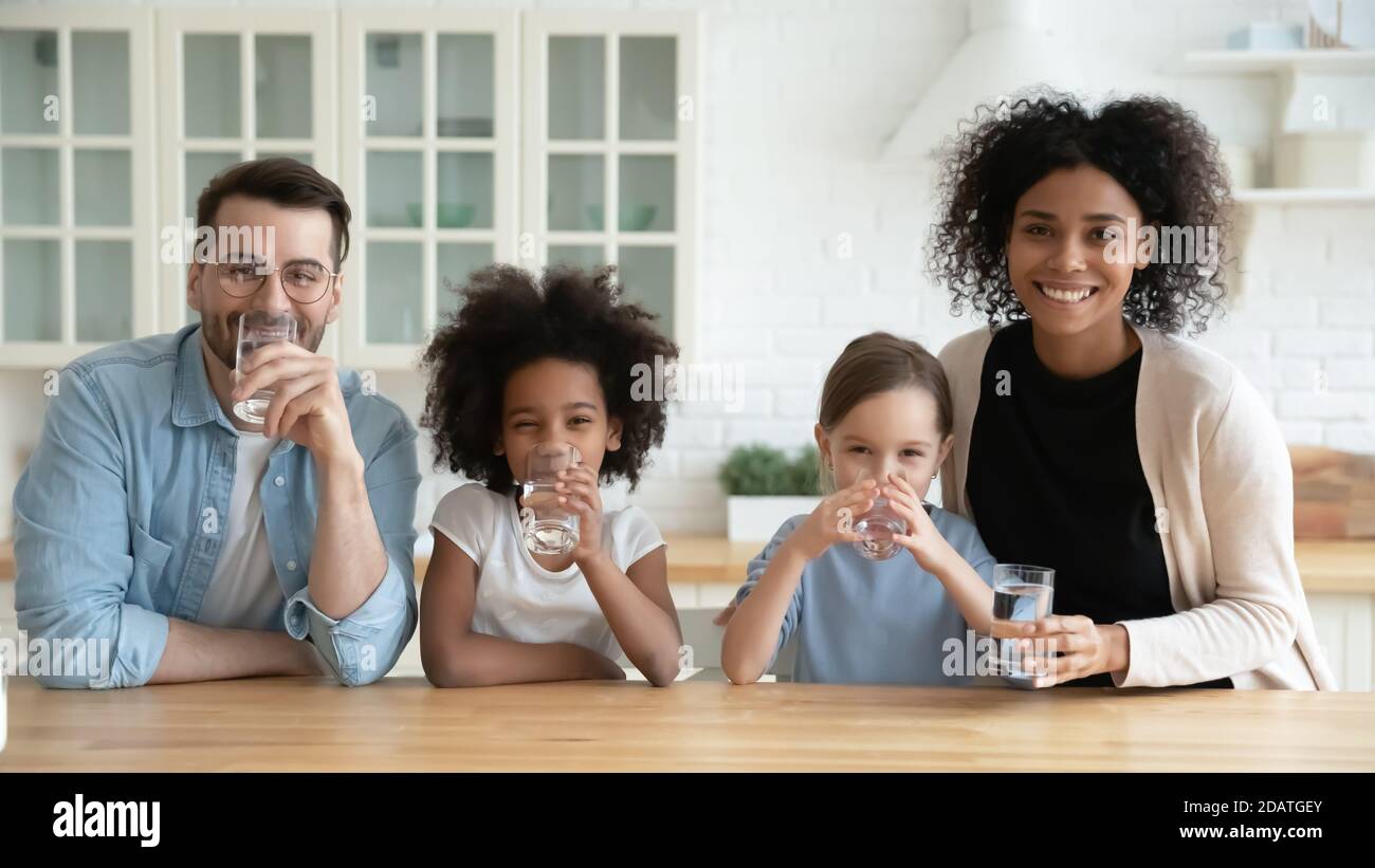 Happy multiracial family drinking pure mineral water in kitchen Stock ...