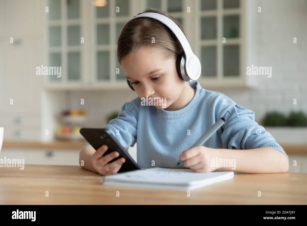 Close up focused little girl wearing headphones using phone Stock Photo ...