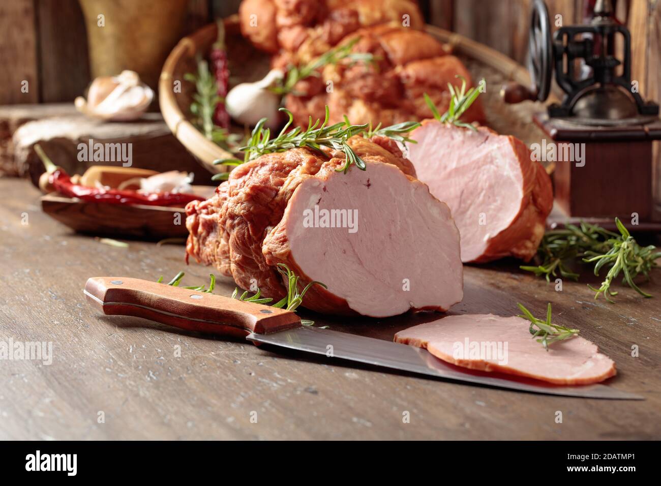 Smoked ham with herbs, spices, and kitchen utensils on an old wooden ...