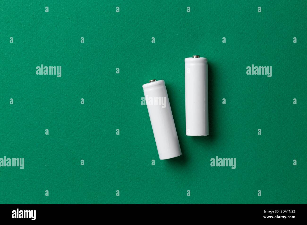 Rechargeable AAA batteries in white on a green background. Place for ...