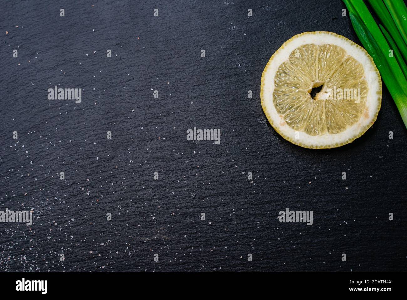 Lemon slice on shale board with green onion. Scattered salt Stock Photo ...