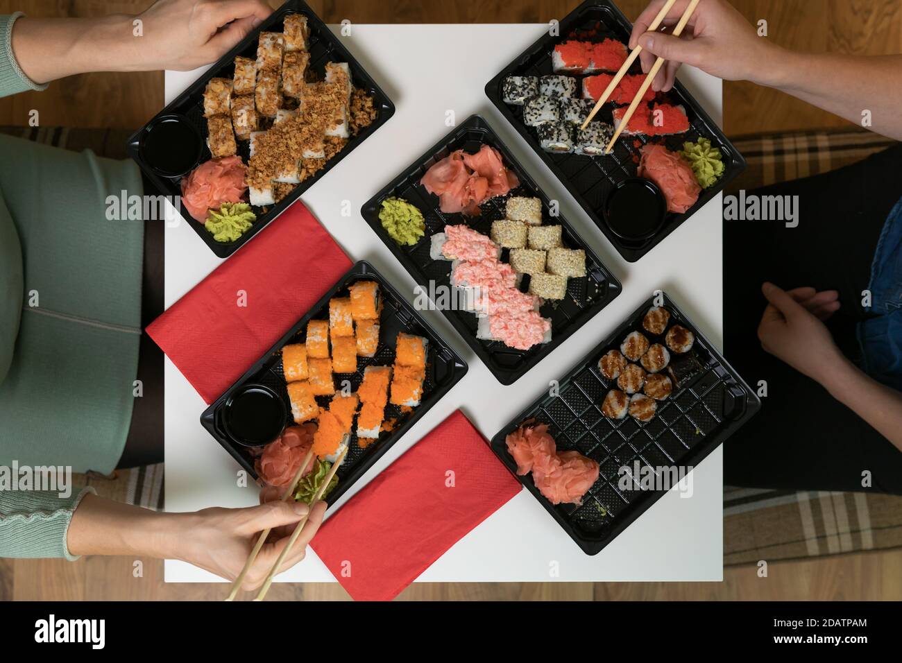 Two women friends sitting by table and eating sushi. Family, friendship ...