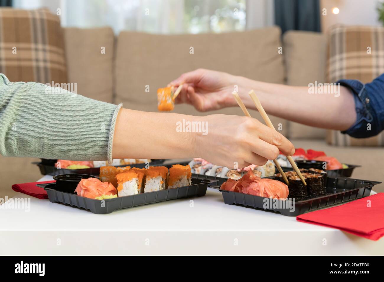 Two women friends sitting by table and eating sushi. Family, friendship ...