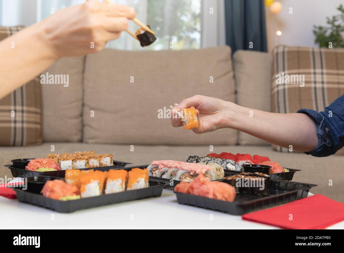Two women friends sitting by table and eating sushi. Family, friendship ...
