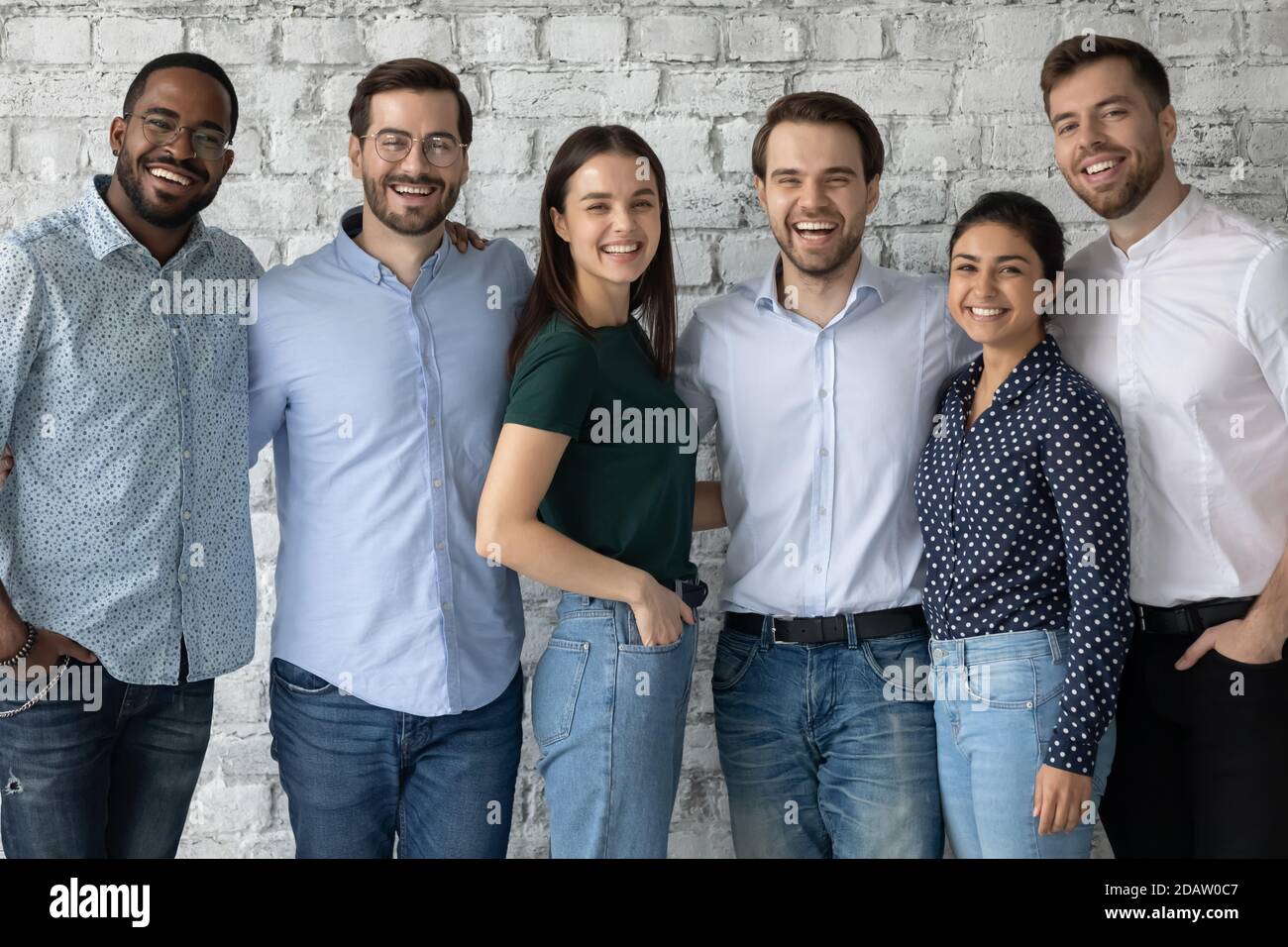 Happy diverse young people teammates hugging and looking at camera ...
