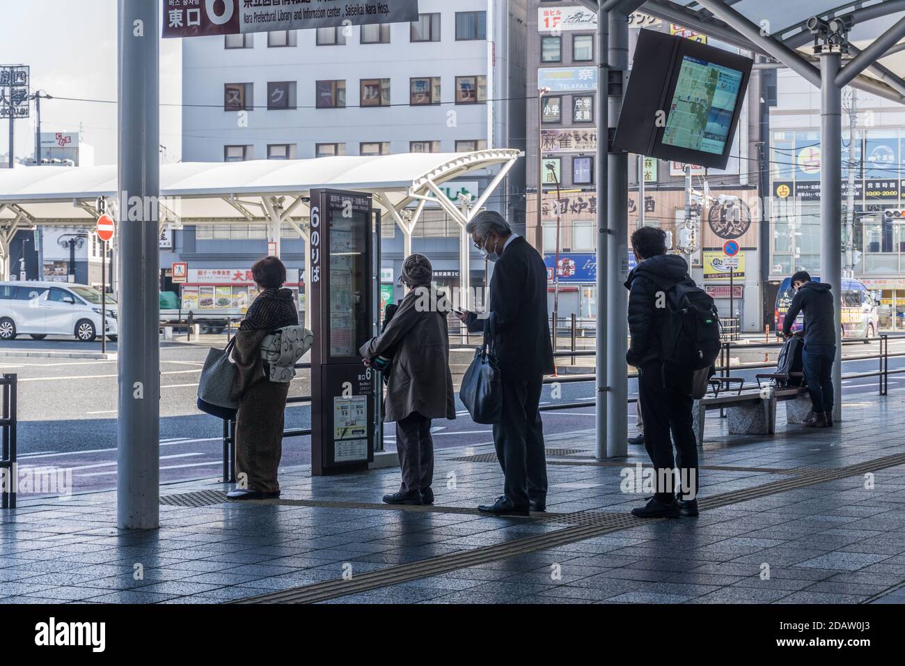 Passengers waiting in a line at a bus stop outside JR Nara Station in ...