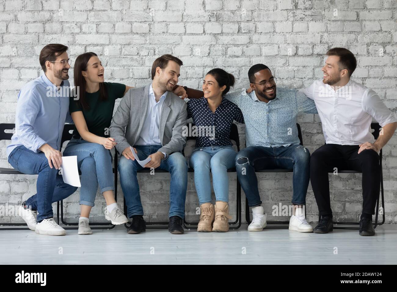 Friendly diverse colleagues sitting on chairs hugging talking ...