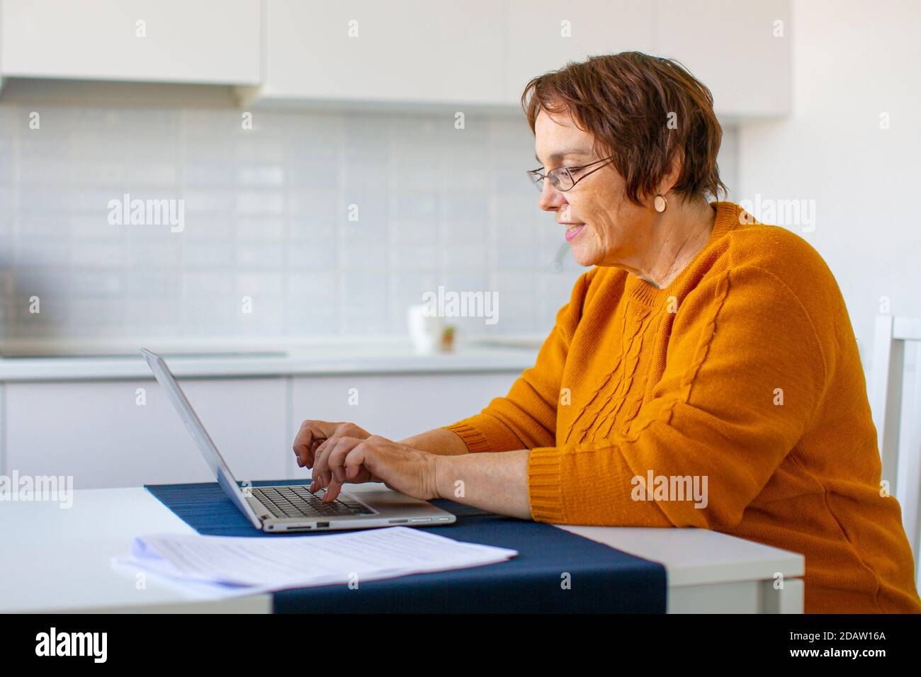 Photo of a smiley senior woman filling forms online in home interior ...