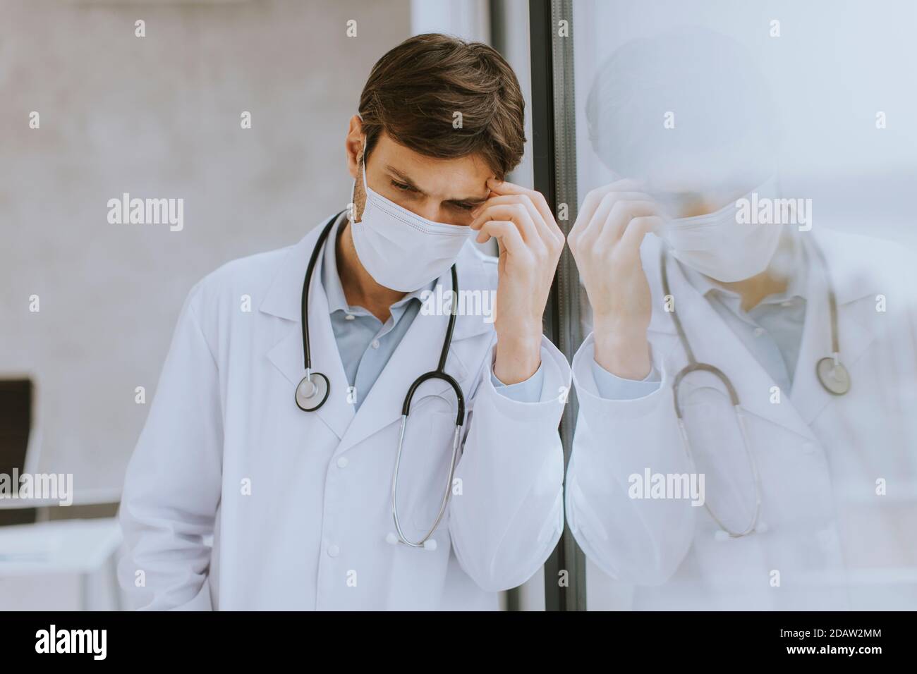 Handsome male doctor looking away with worry, frustration, tiredness ...