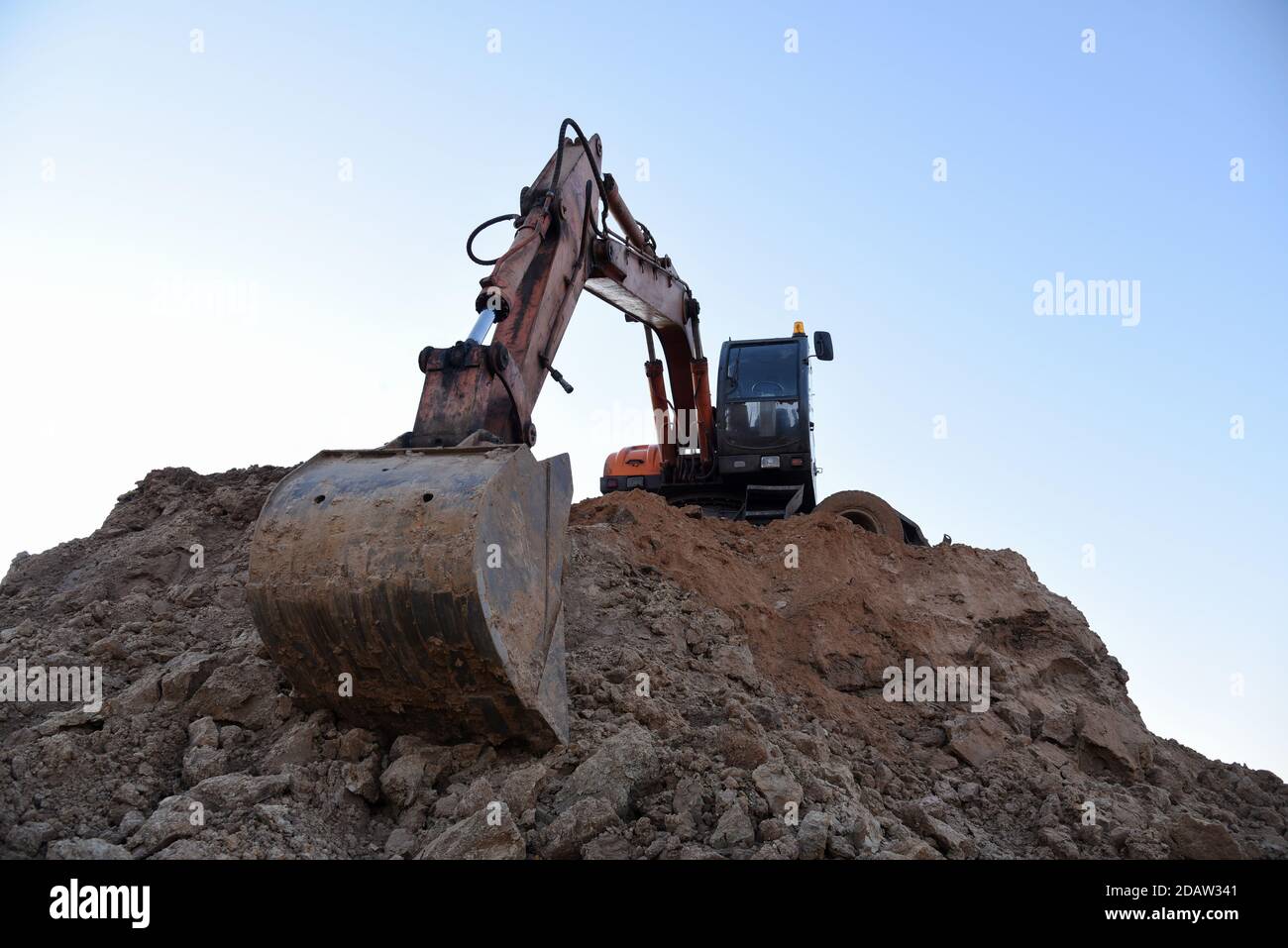 Excavator during earthmoving work at open-pit mining on sunset ...