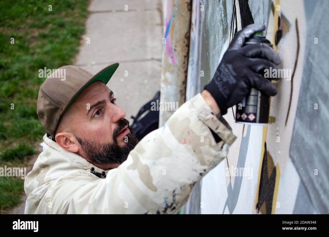 Graffiti artist in action, painting on the wall with aerosol spray ...