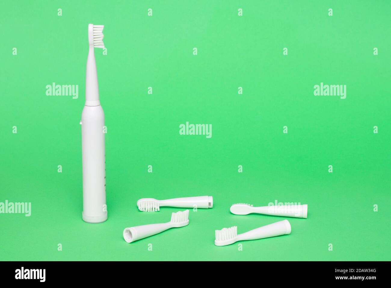 White wireless electric toothbrush with replaceable heads on a light ...