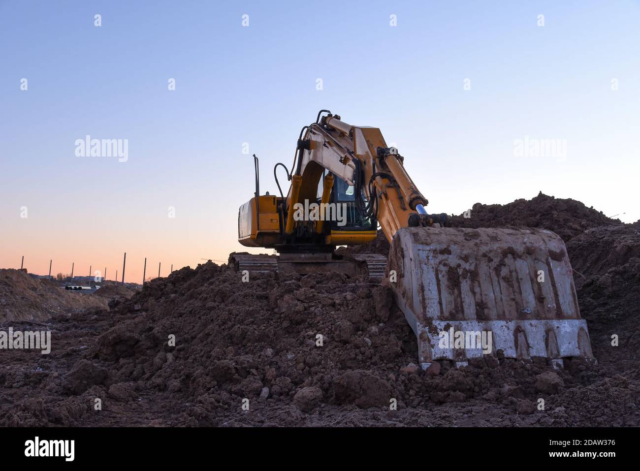 Excavator during earthmoving work at open-pit mining on sunset ...