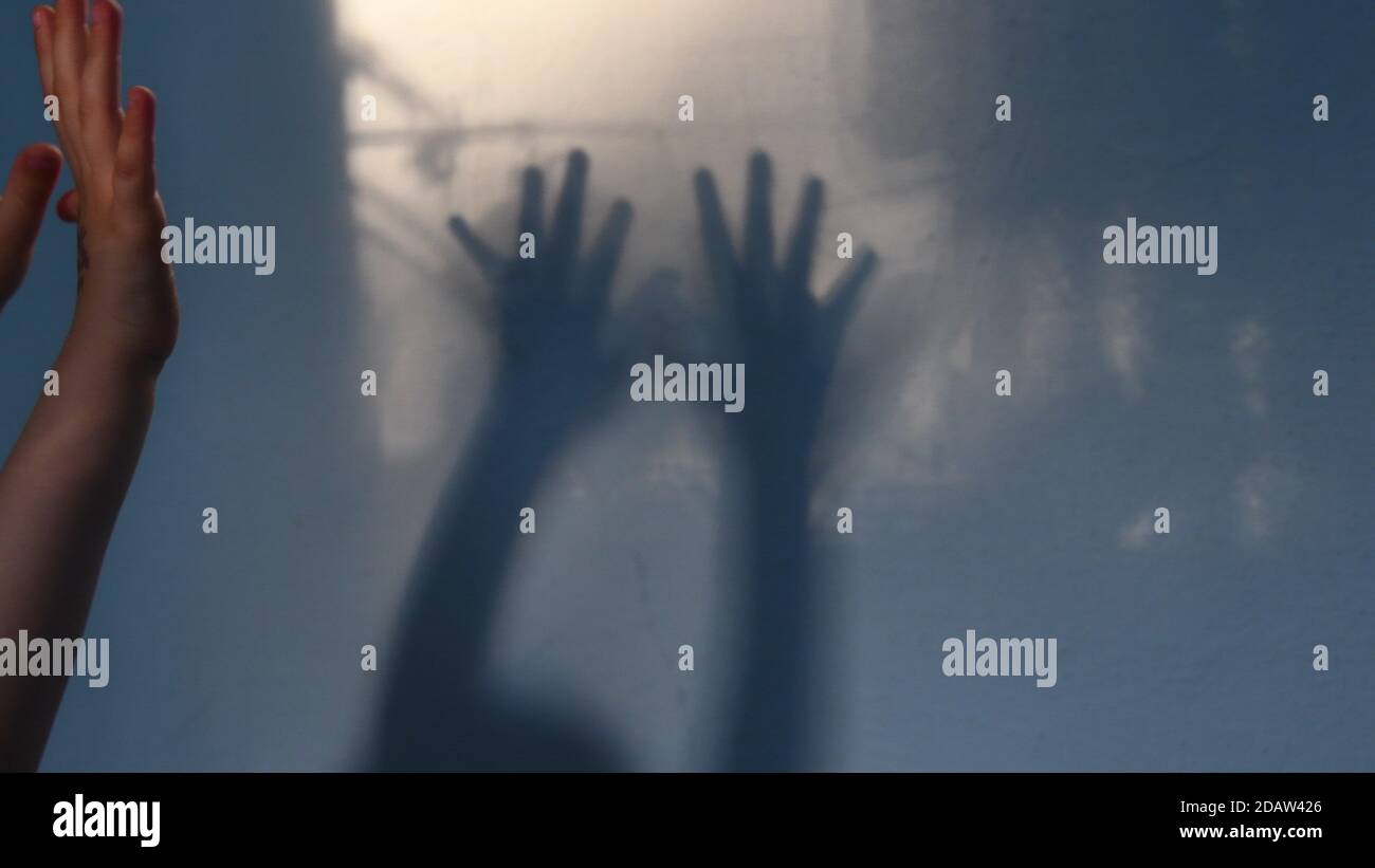 Blur shadows of child hands on wall. Game with light and shadow. Dark ...