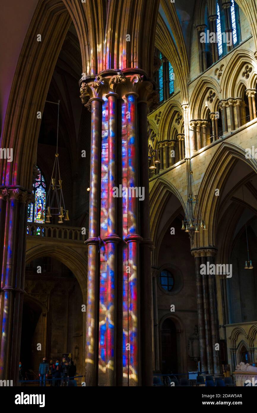 Support column with stained glass window pattern projected by sunlight ...