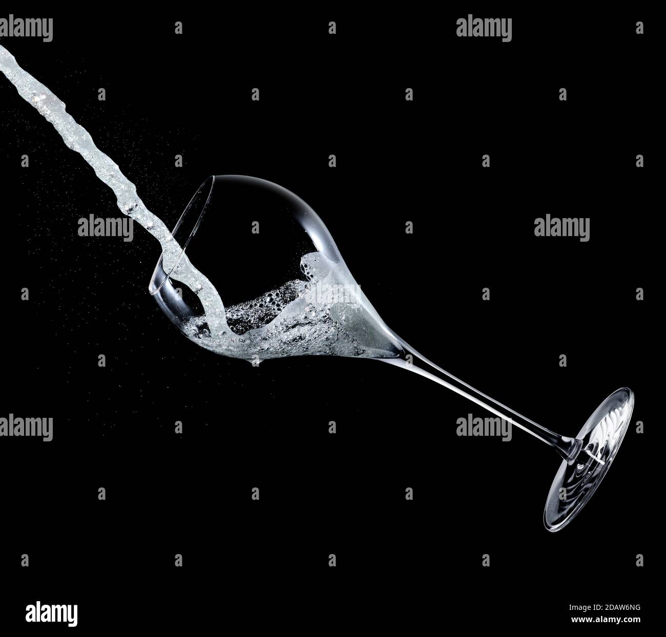 Prosecco wine is poured into a glass with splashes. On black background ...